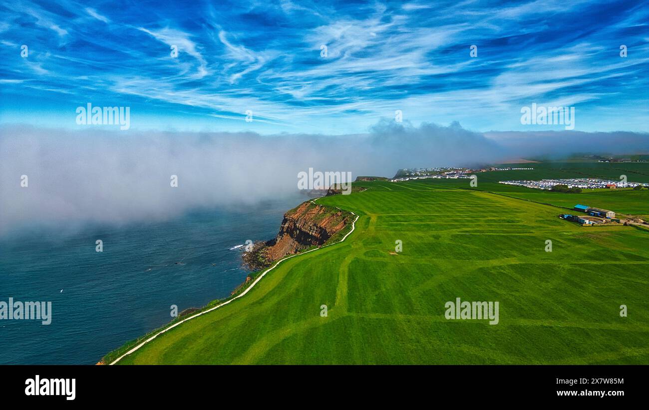 Aerial view of a coastal landscape with green fields, cliffs, and the ...