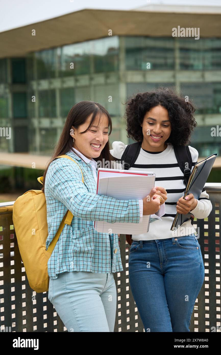 Two multiethnic students sharing notes outside the University Stock ...