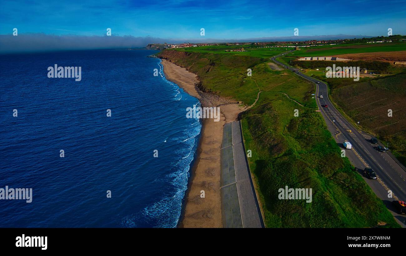 Aerial view of a coastal road running parallel to a beach with blue ...