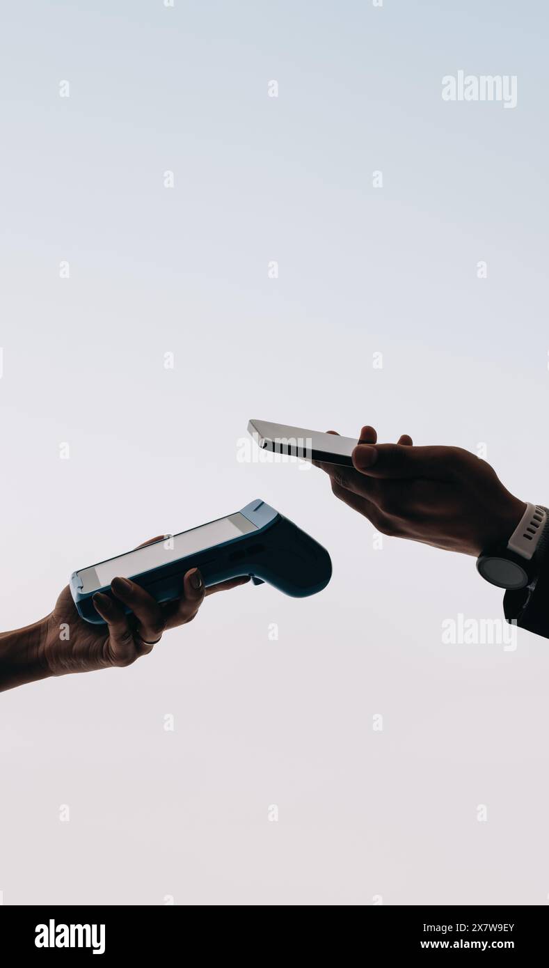 Hands holding a smartphone and a card machine close to each other ...