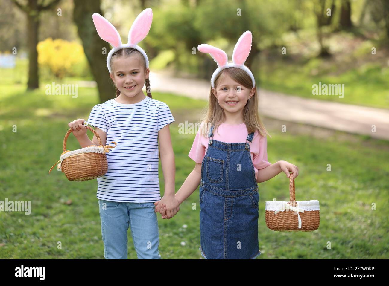 Easter celebration. Cute little girls with bunny ears holding wicker ...