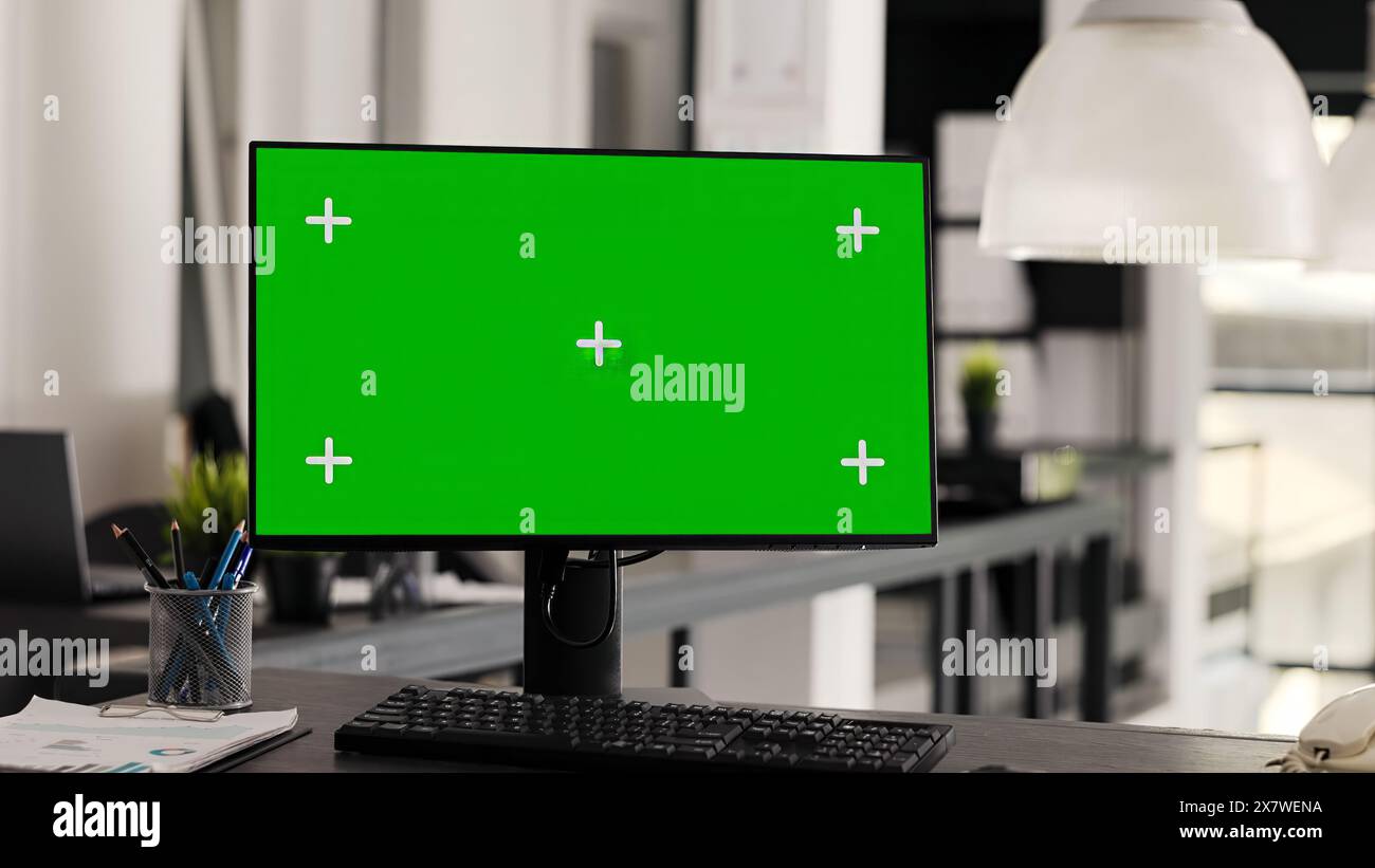 Empty workstation with computer running greenscreen on monitor, showing blank chromakey template ...