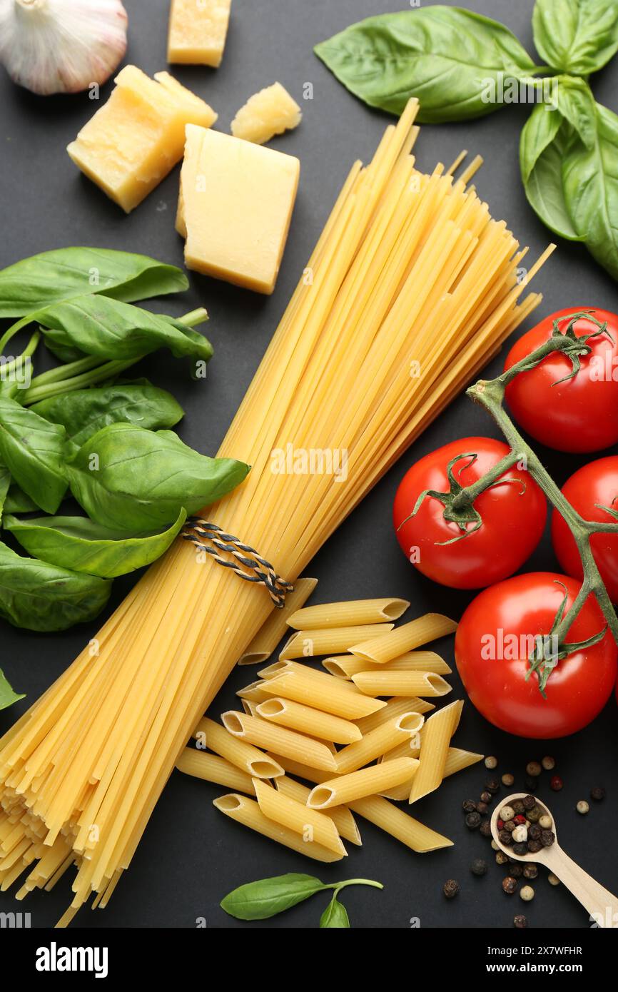 Different types of pasta, spices and products on black background, flat ...