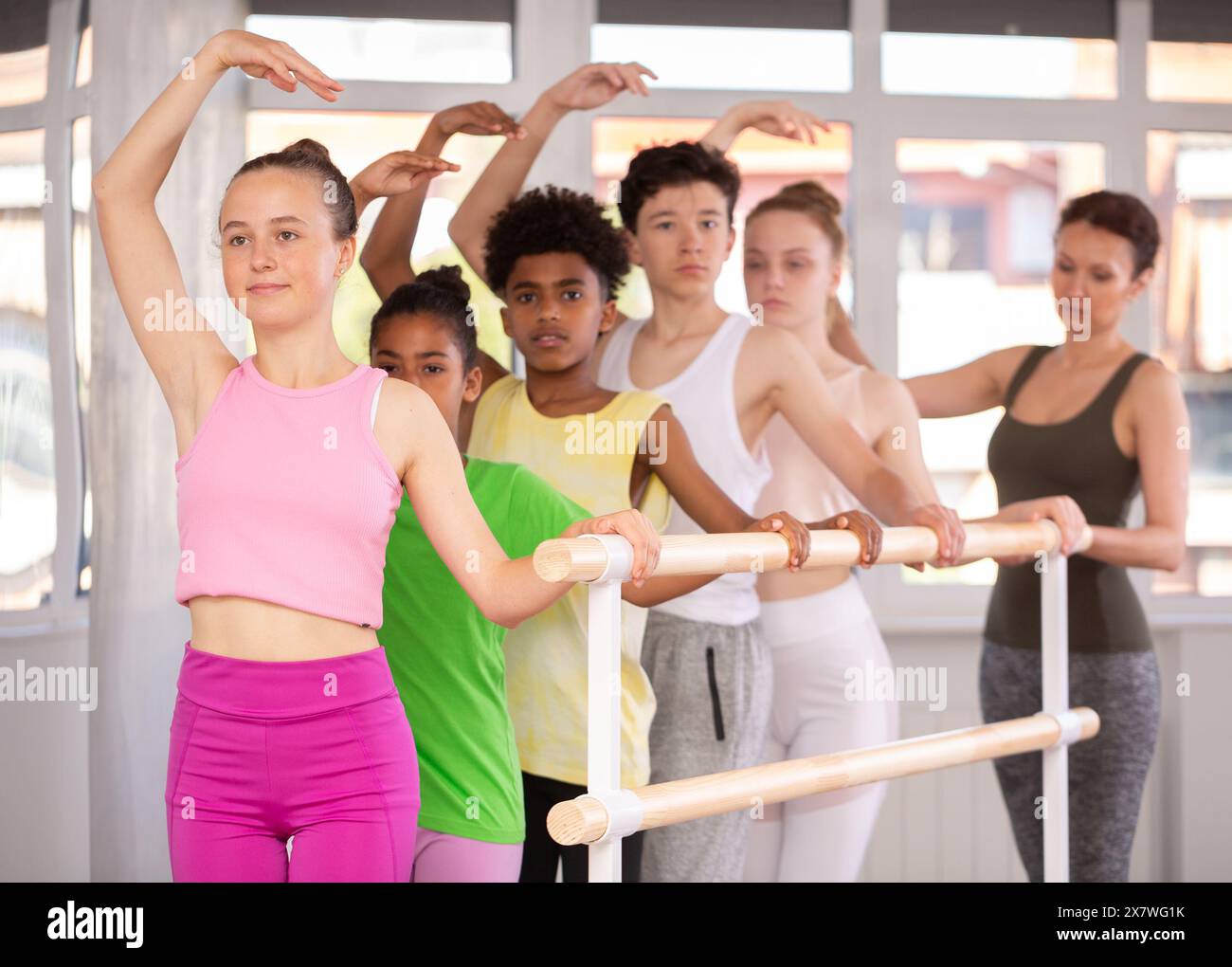 Woman teacher corrects teenagers in first position Stock Photo - Alamy