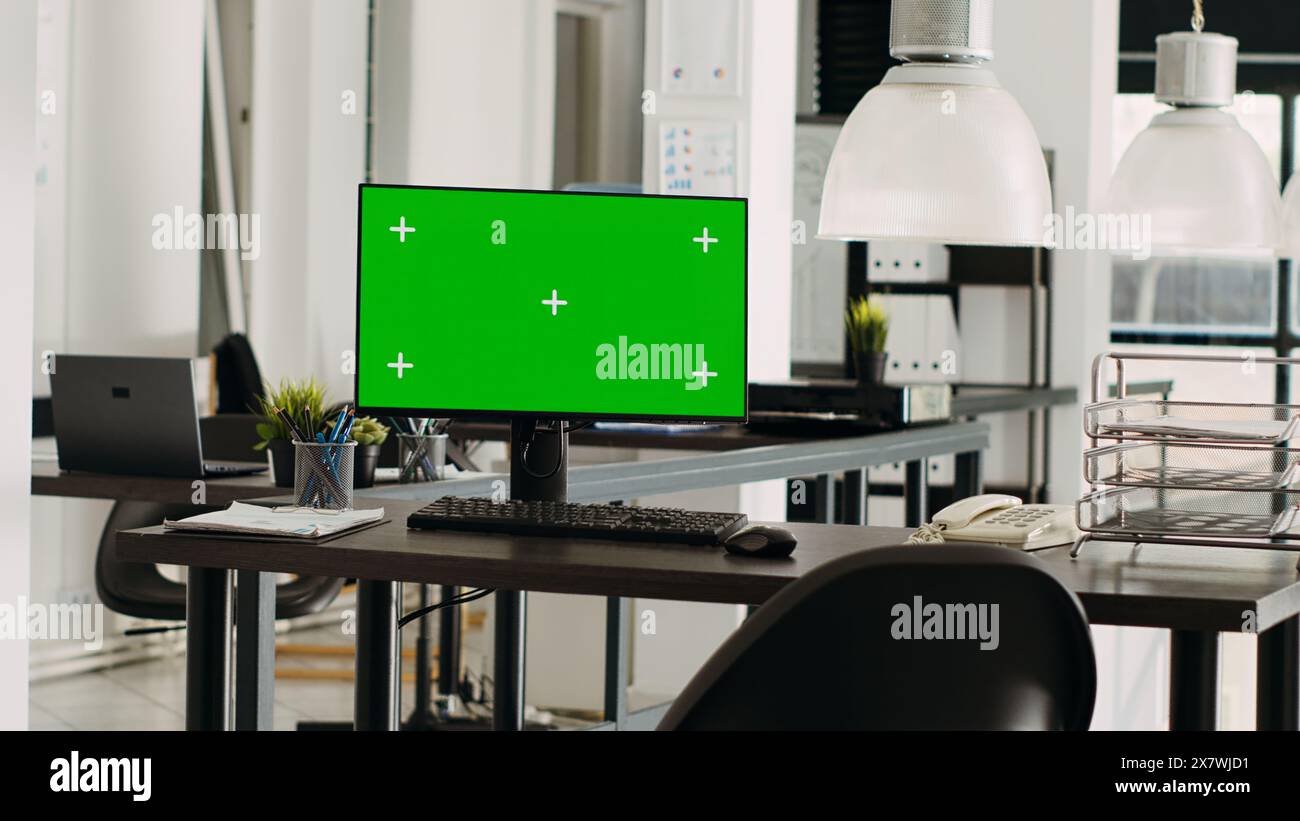Greenscreen monitor in coworking space running on desk, open floor plan ...