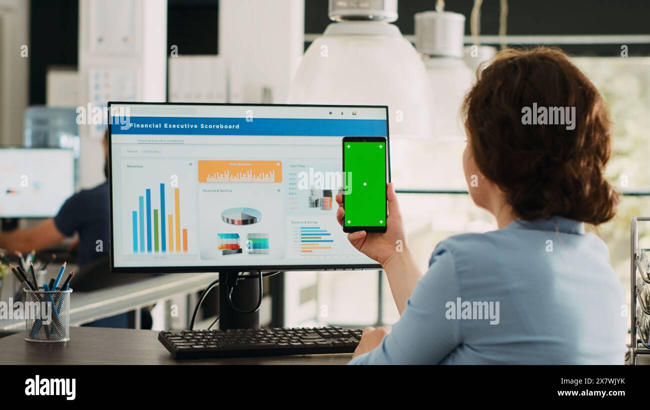 Employee looks at greenscreen on phone, working on business operations ...