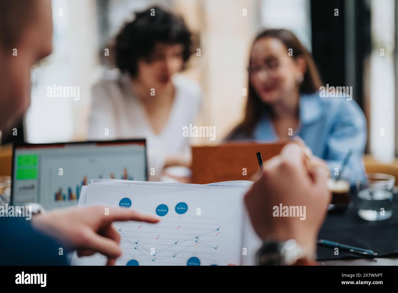Team collaboration during business meeting with focus on graph ...