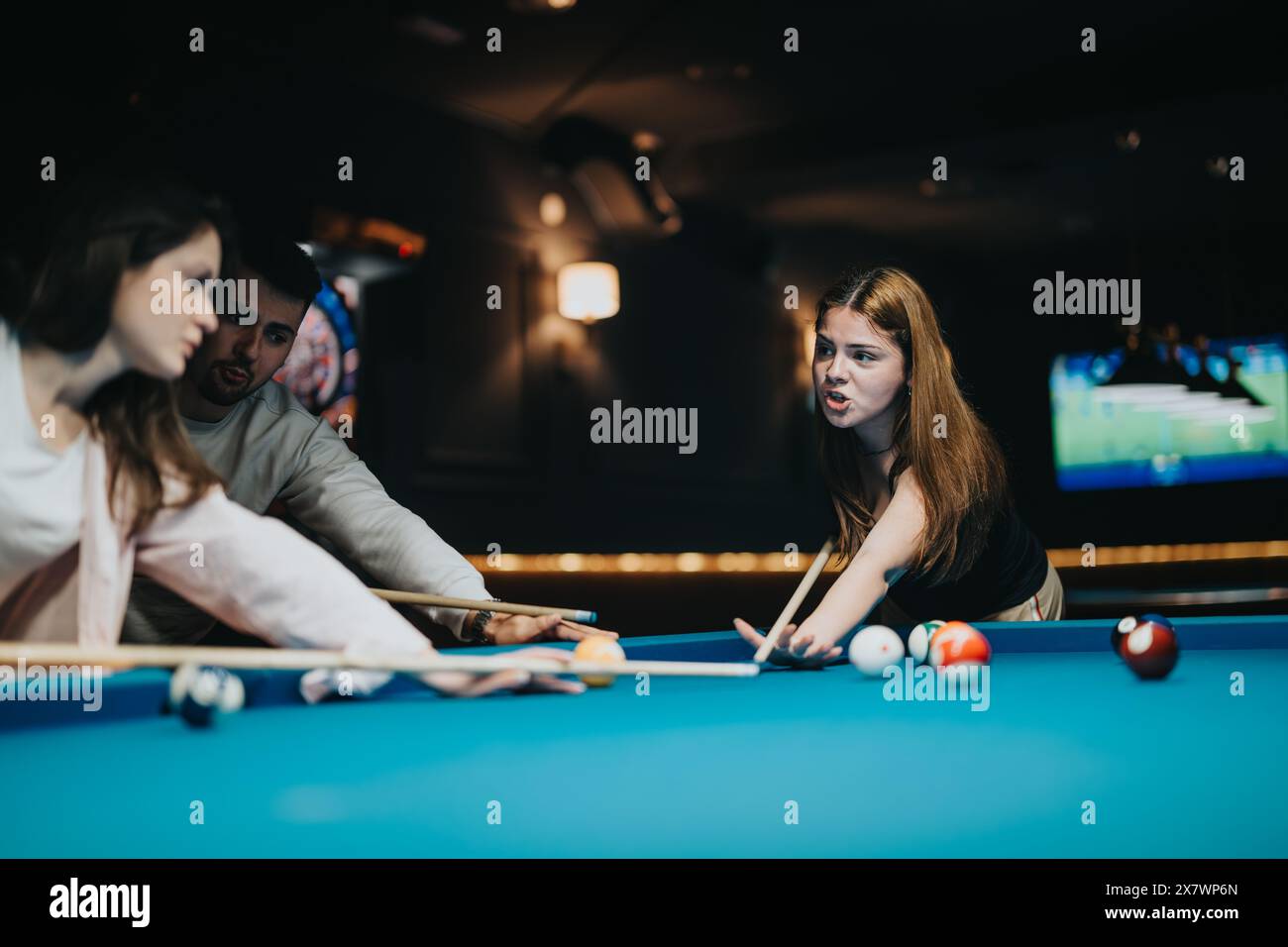 Young friends having fun playing a competitive game of billiards in a ...