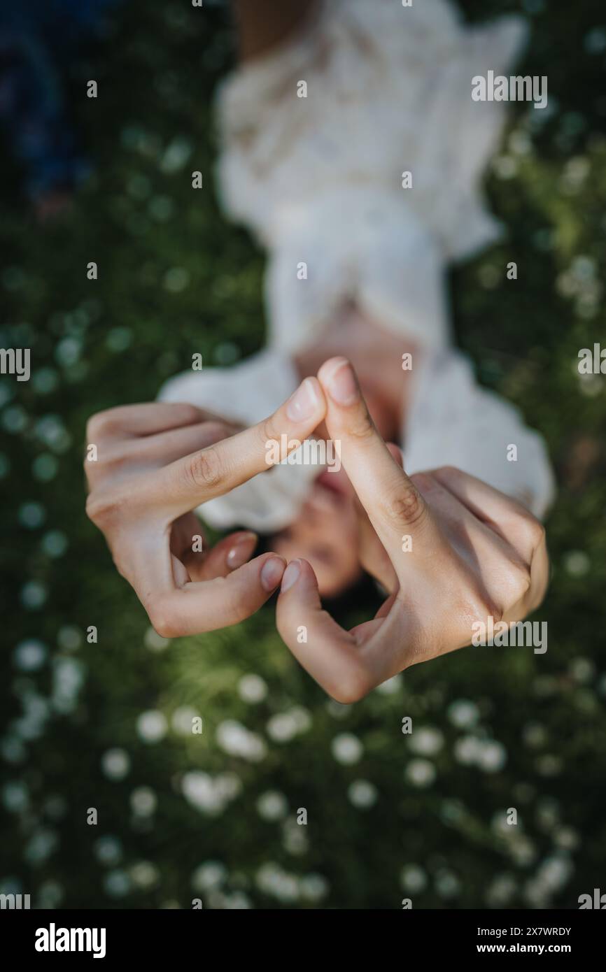 Child making heart shape with hands while lying in a grassy park Stock ...