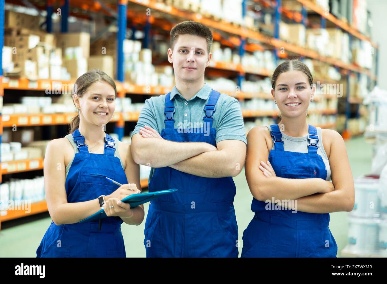 Three store employees posing near stand with goods in construction ...