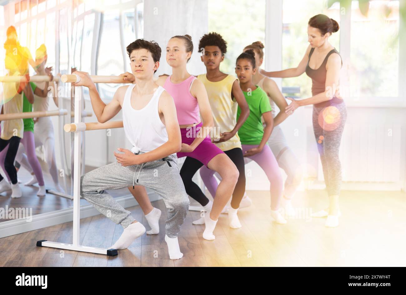 Woman teacher corrects teenagers in plie movement Stock Photo - Alamy