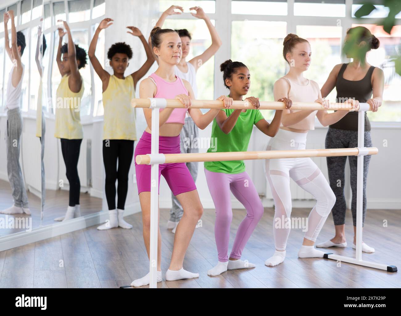 Woman teacher corrects teenagers in plie movement Stock Photo - Alamy