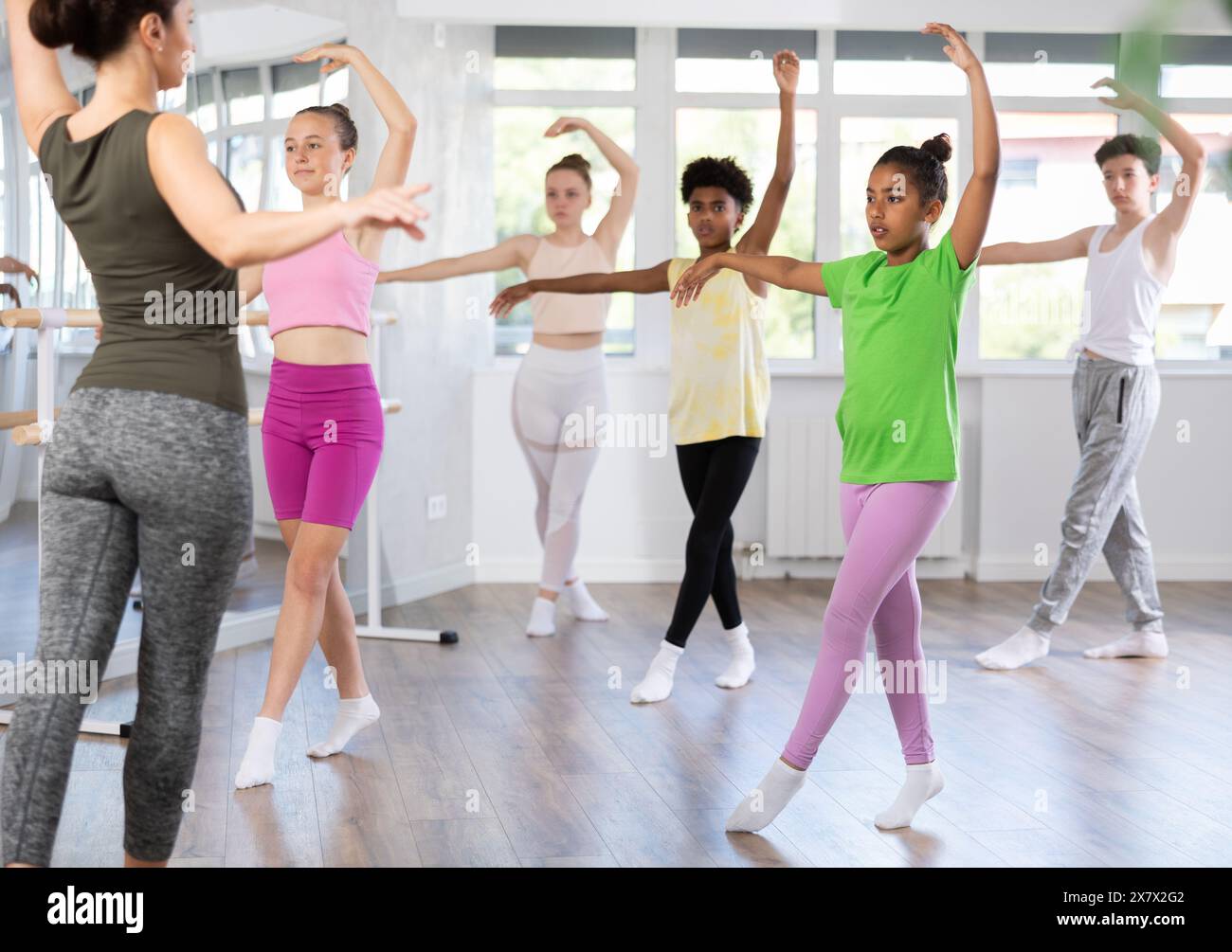 Slender teen girl doing fourth position of ballet in group during choreography classes Stock ...