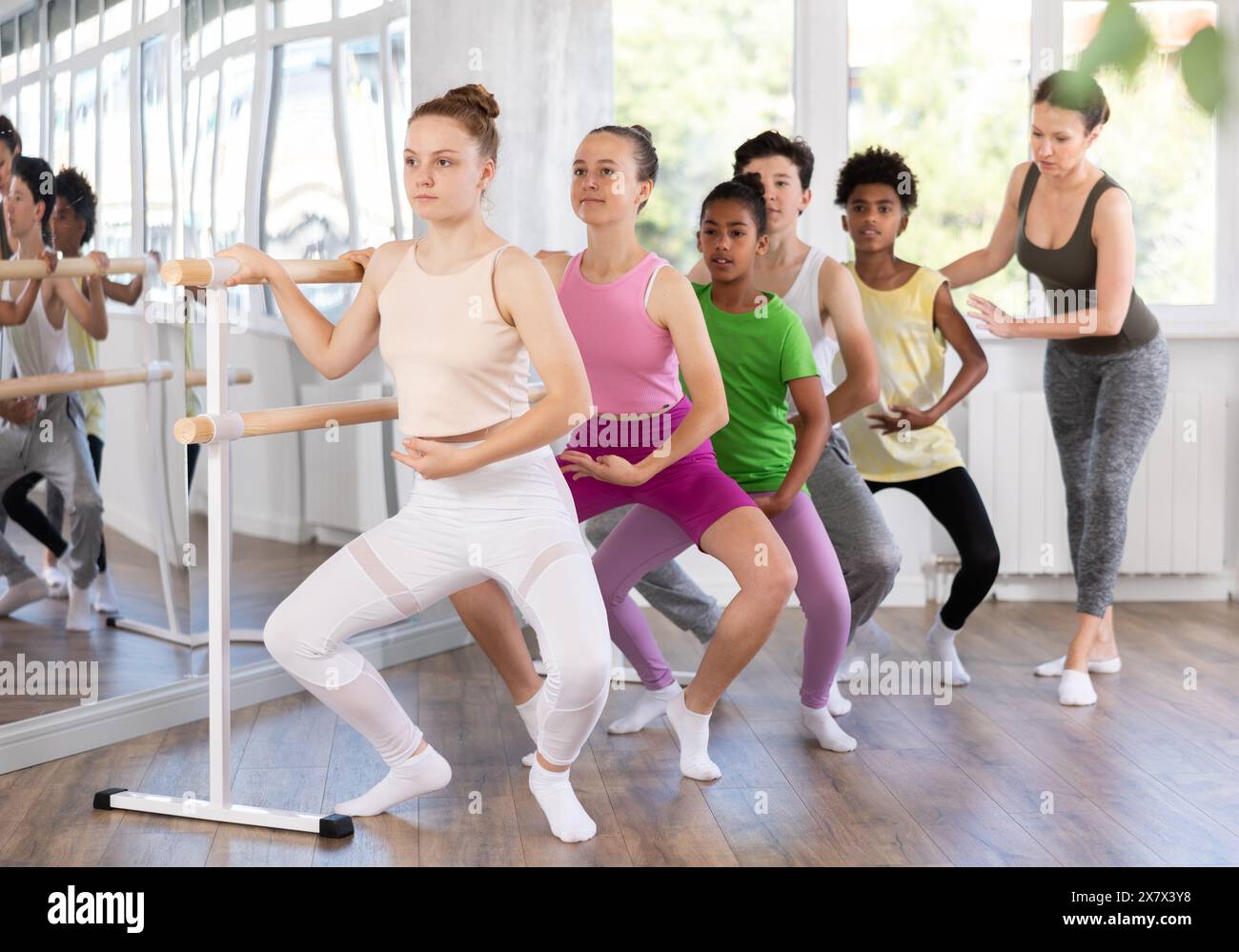 Woman teacher corrects teenagers in plie movement Stock Photo - Alamy