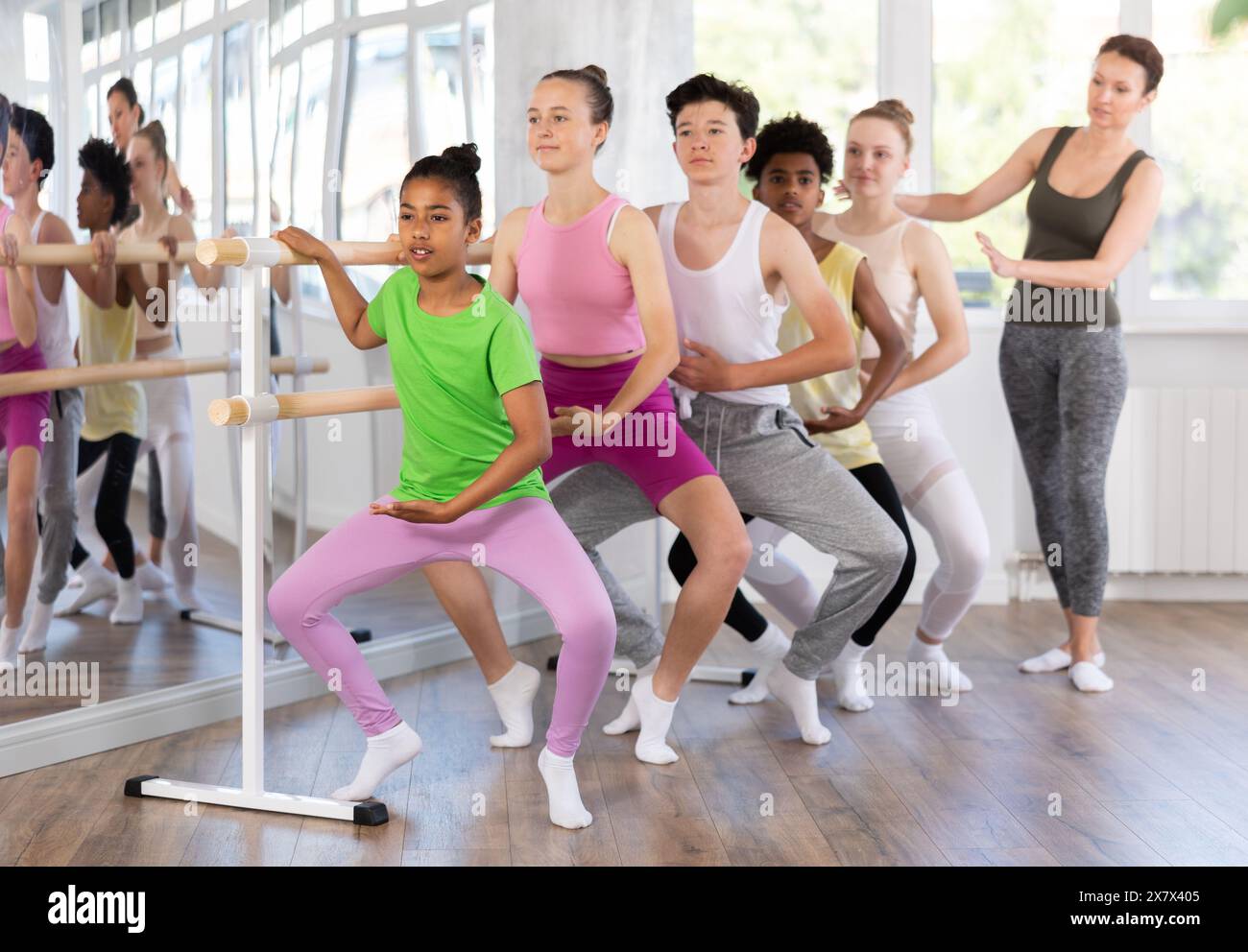 Woman teacher corrects teenagers in plie movement Stock Photo - Alamy