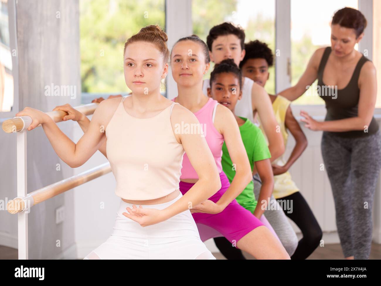 Woman teacher corrects teenagers in plie movement Stock Photo - Alamy