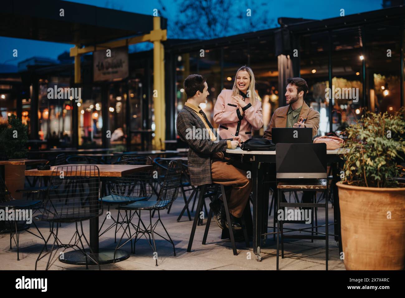 Business colleagues laughing together during an outdoor meeting at a cafe Stock Photo - Alamy