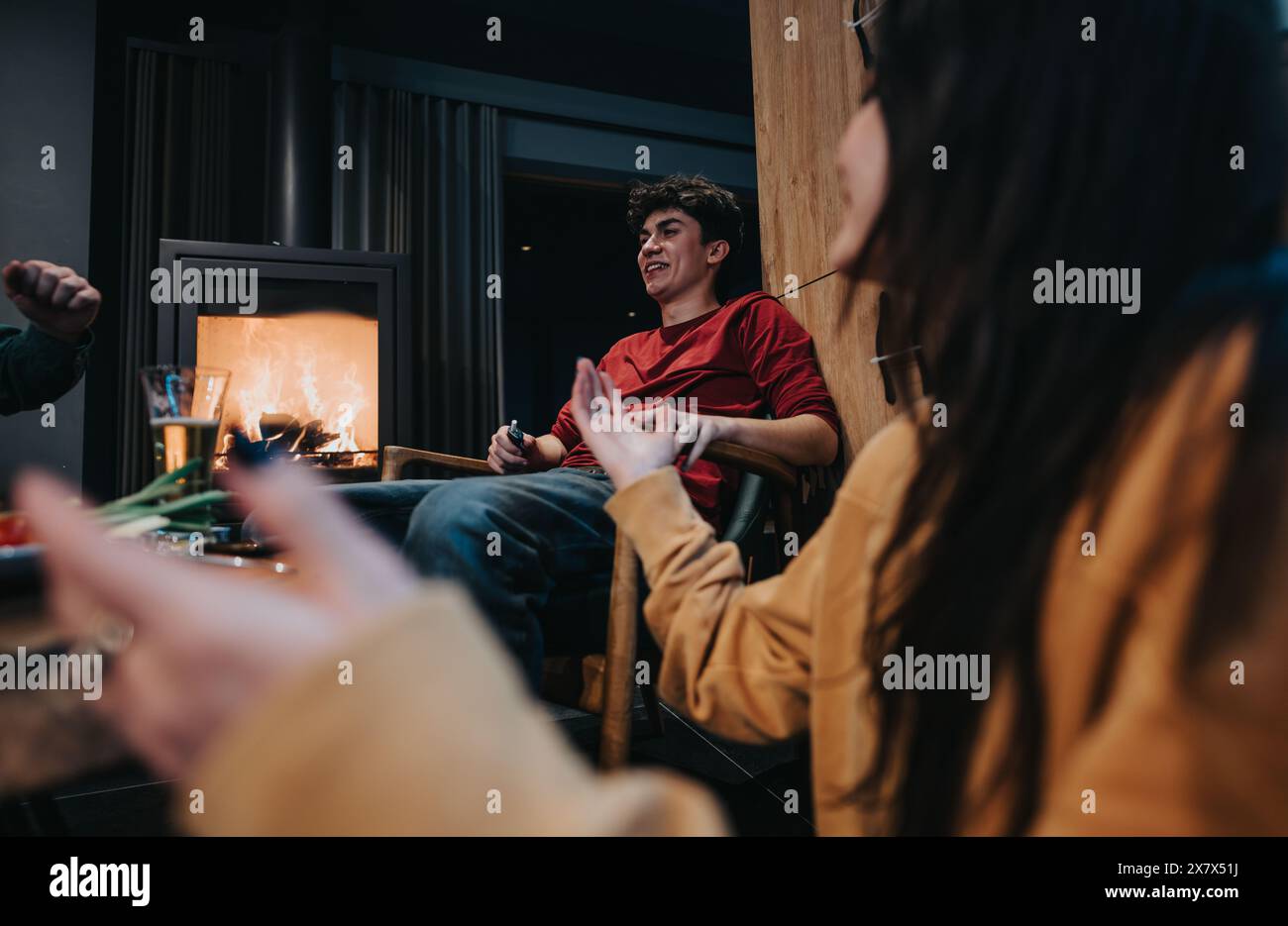 Group of friends enjoying a cozy evening chat by the fireplace at home ...