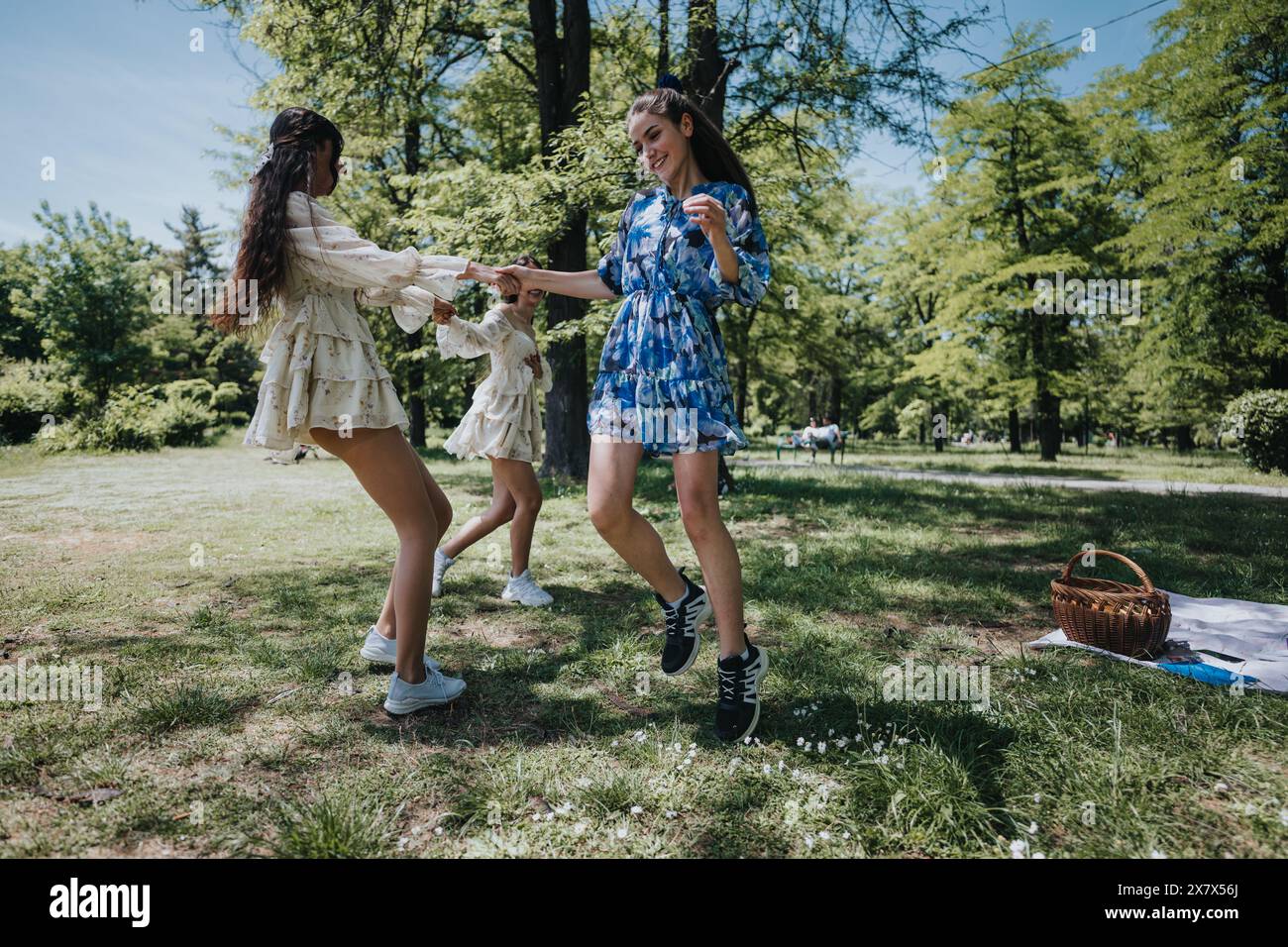 Joyful sisters dancing in a circle in a sunny park, expressing ...