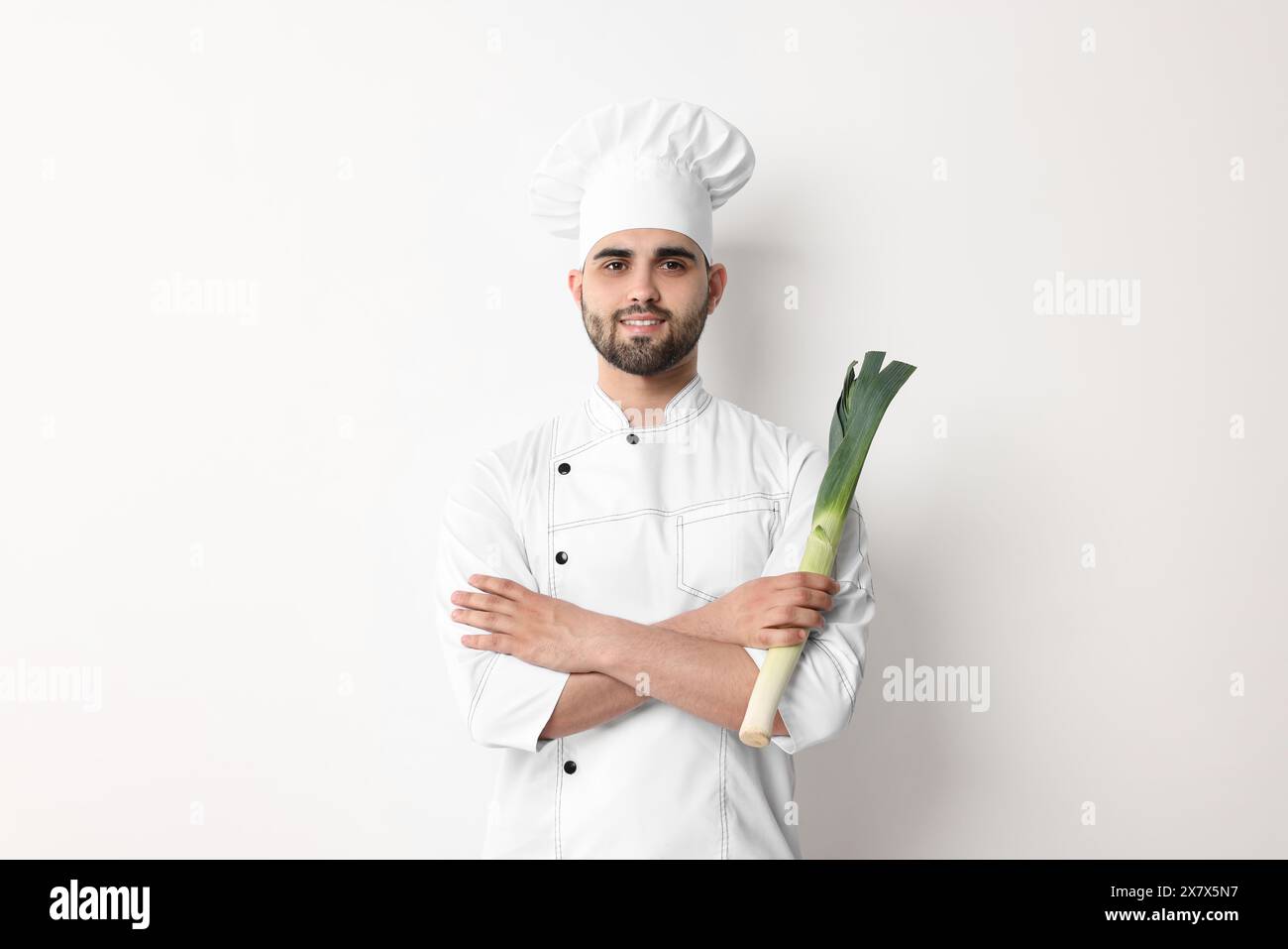 Professional chef holding leek on white background Stock Photo - Alamy