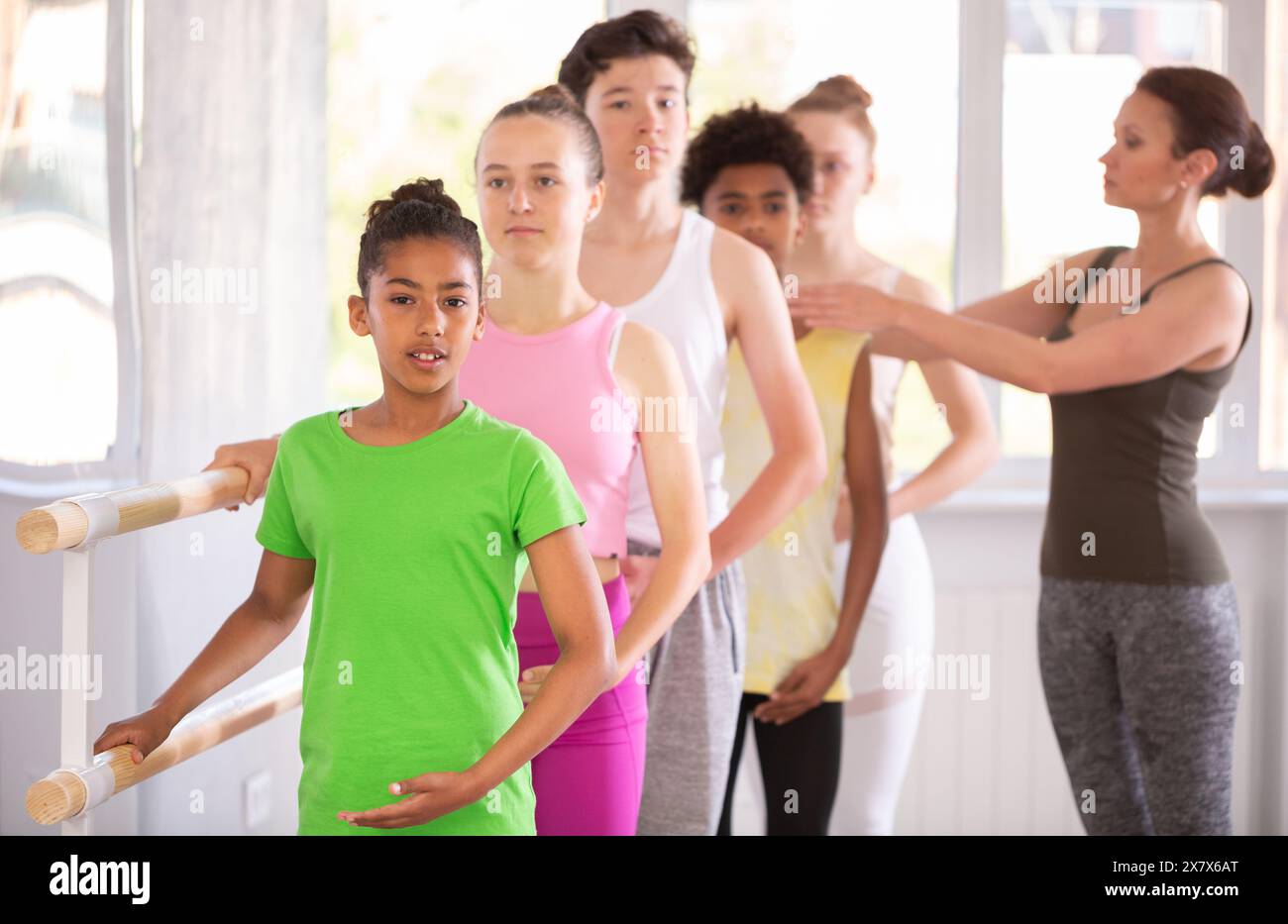 African American teen girl mastering first ballet position at barre ...