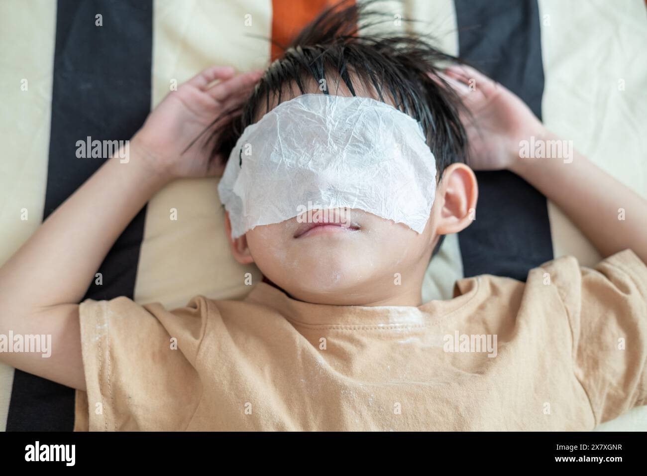 Little Asian boy playing with tissues on his face Stock Photo - Alamy