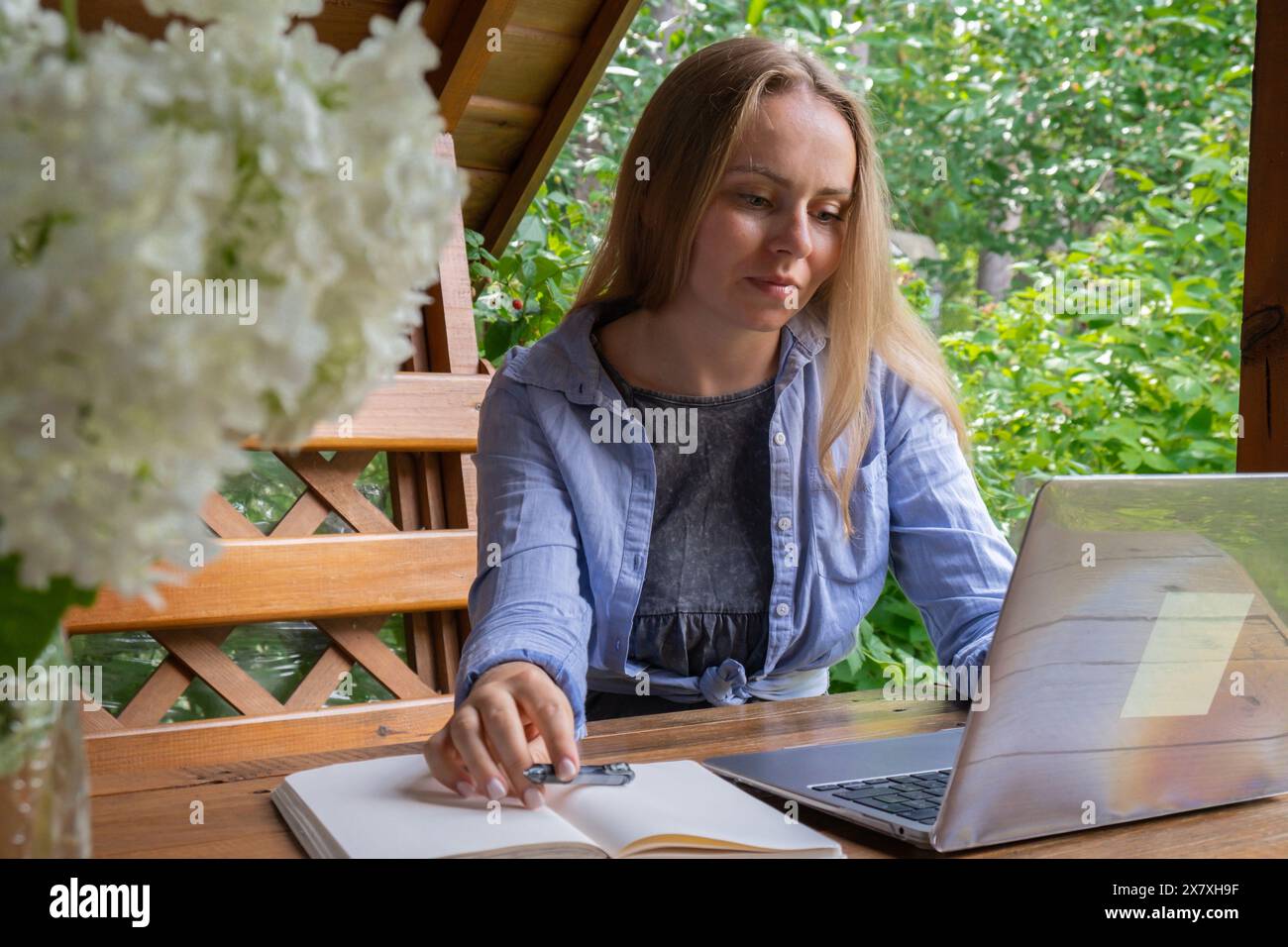 Female student has online lesson education outdoor in garden wooden ...