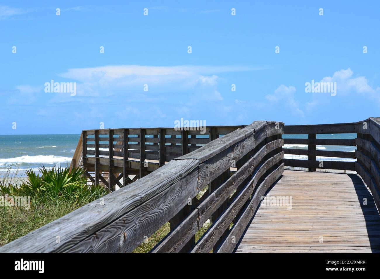 A wooden walkway, nestled beside the dunes, guides you to the beach and ...