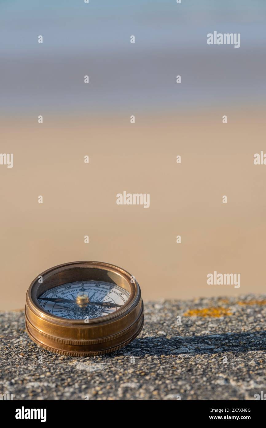 Compass on stone ledge overlooking ocean sand and sky in bakground ...