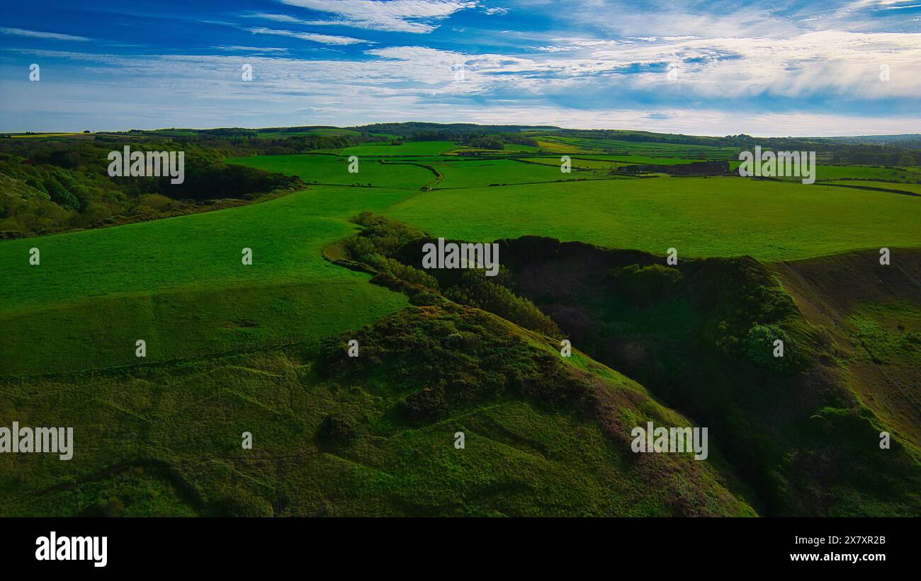 Aerial view of lush green fields and rolling hills under a partly ...