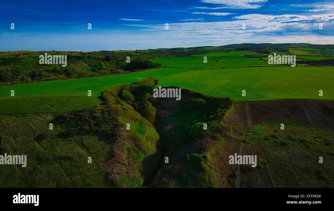 Aerial view of a lush green landscape with rolling hills and a deep ...
