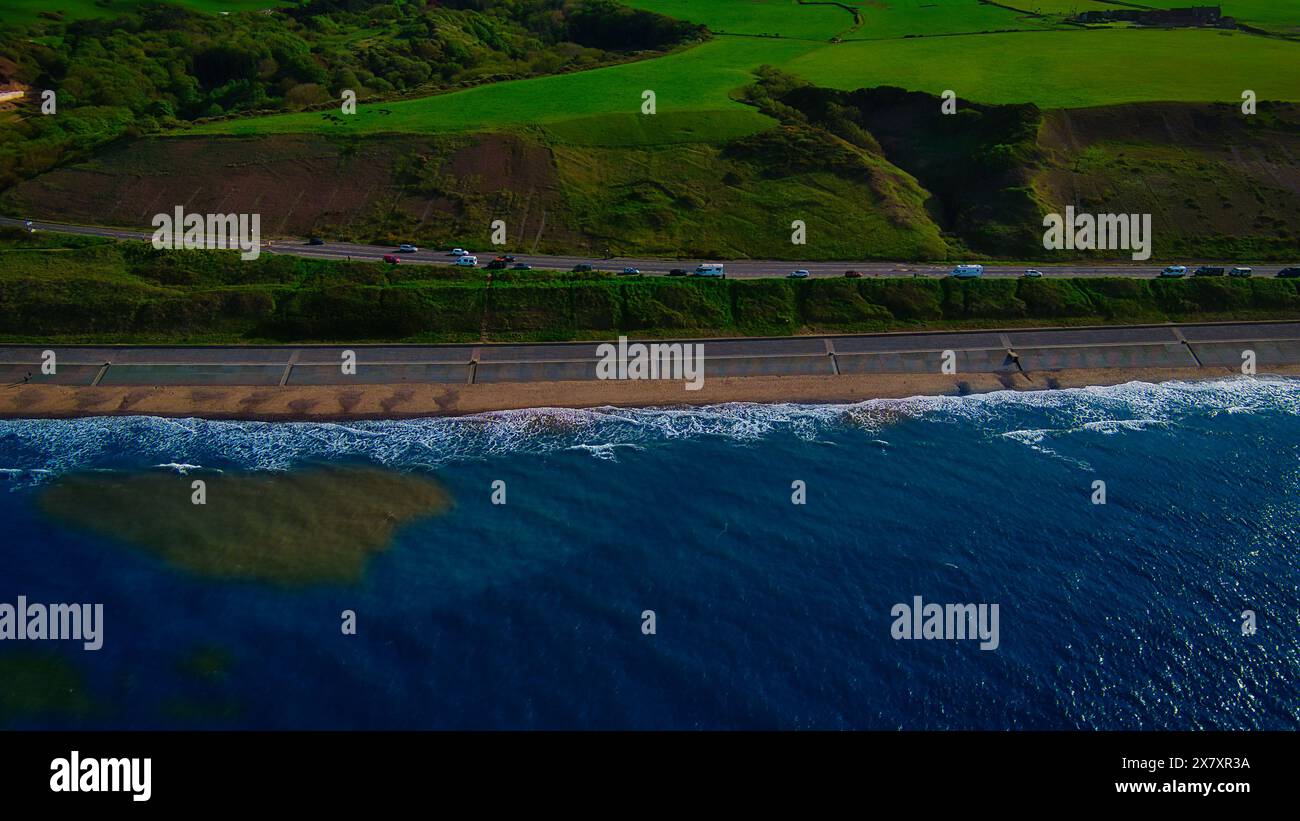Aerial view of a coastal road with vehicles, adjacent to a beach with ...