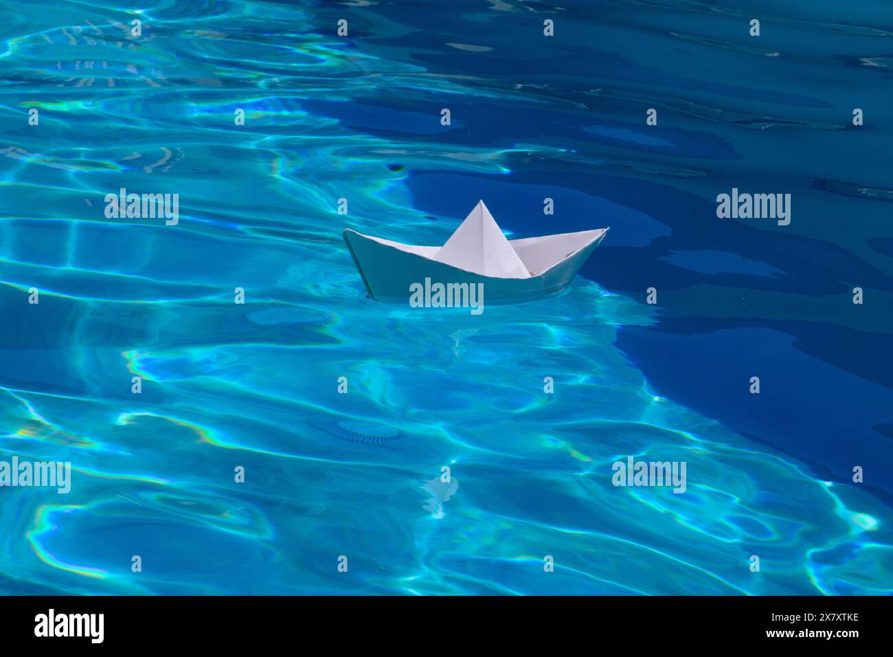 Origami ship. Paper boat sailing on water causing waves and ripples ...