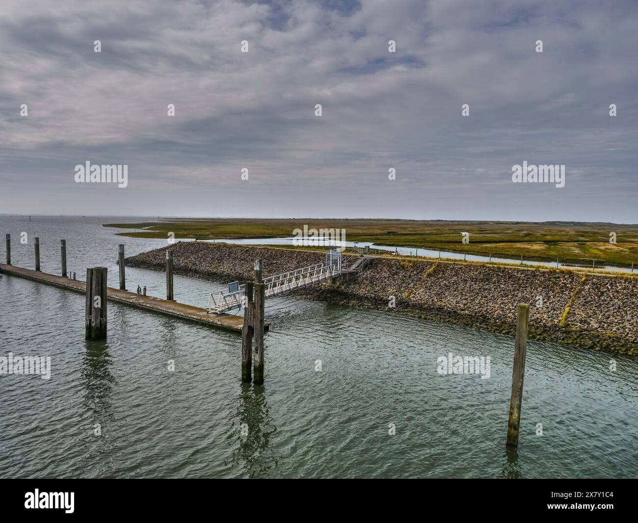 A view of the coast and the sea with a long jetty and cloudy sky, small ...