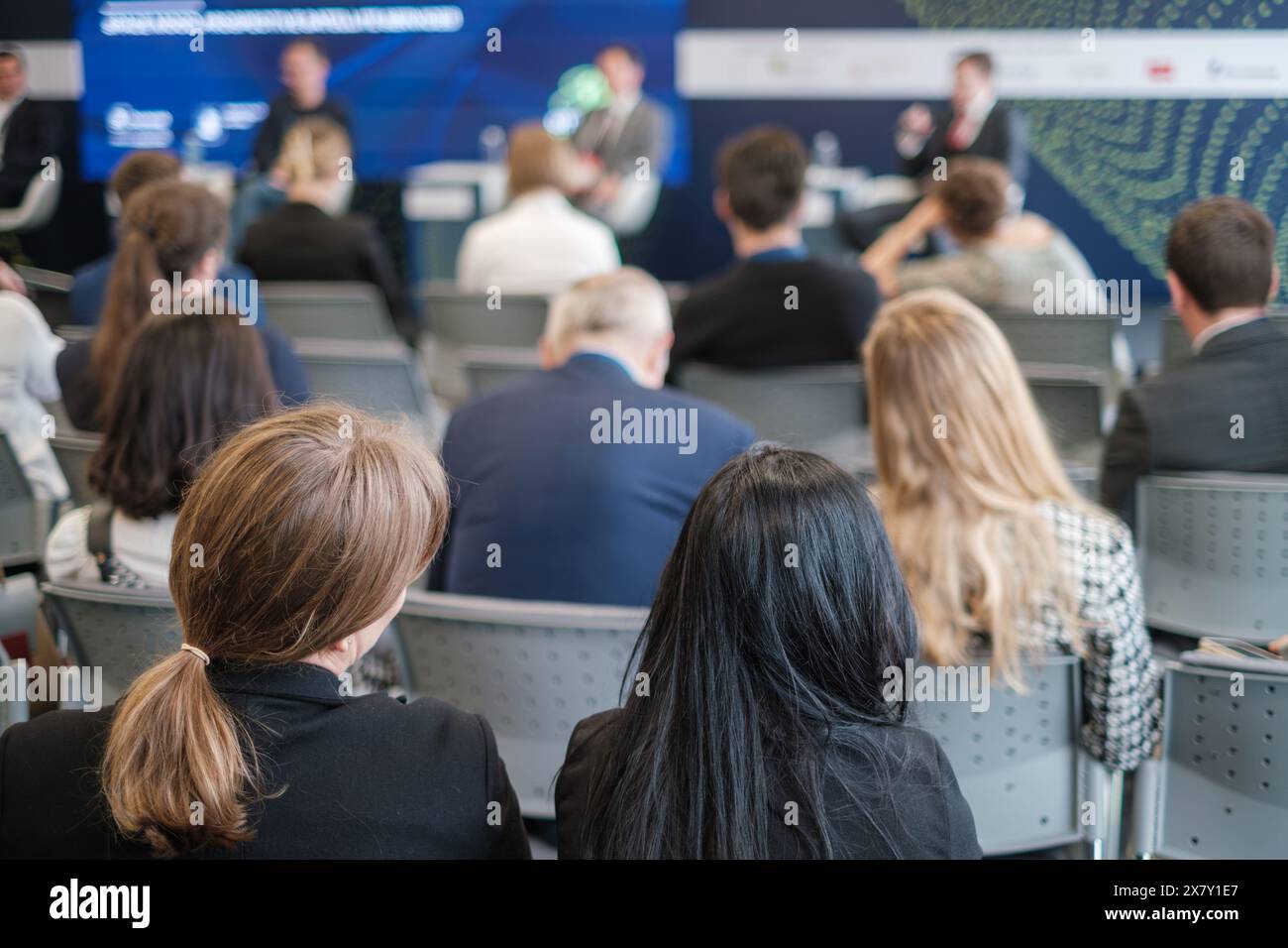 Back view of a diverse audience attending a business conference with ...
