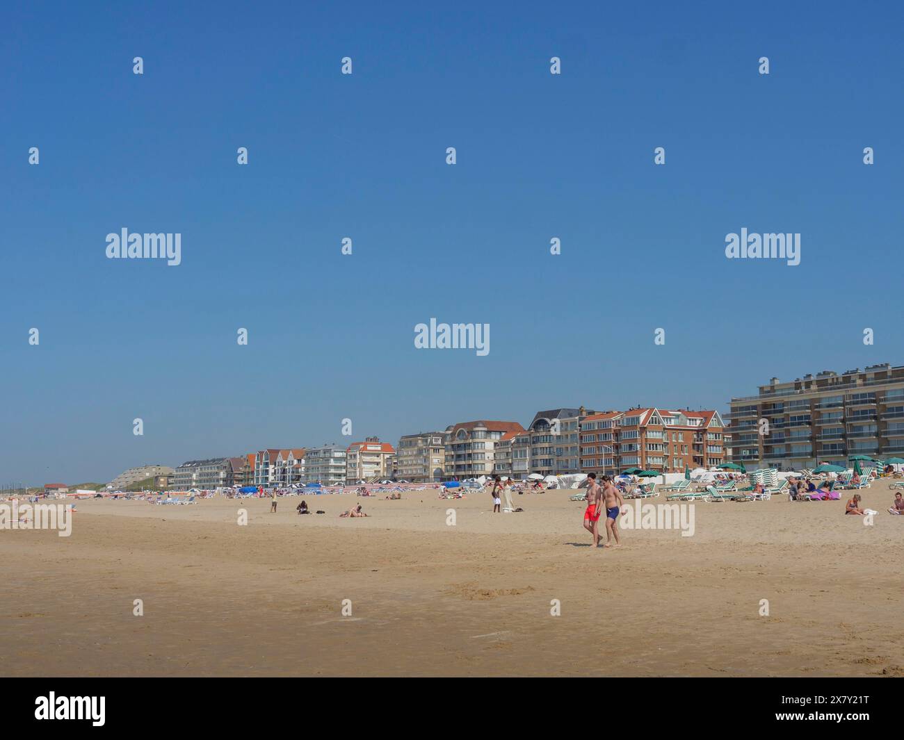 A wide beach with many buildings in the background, in sunny weather ...