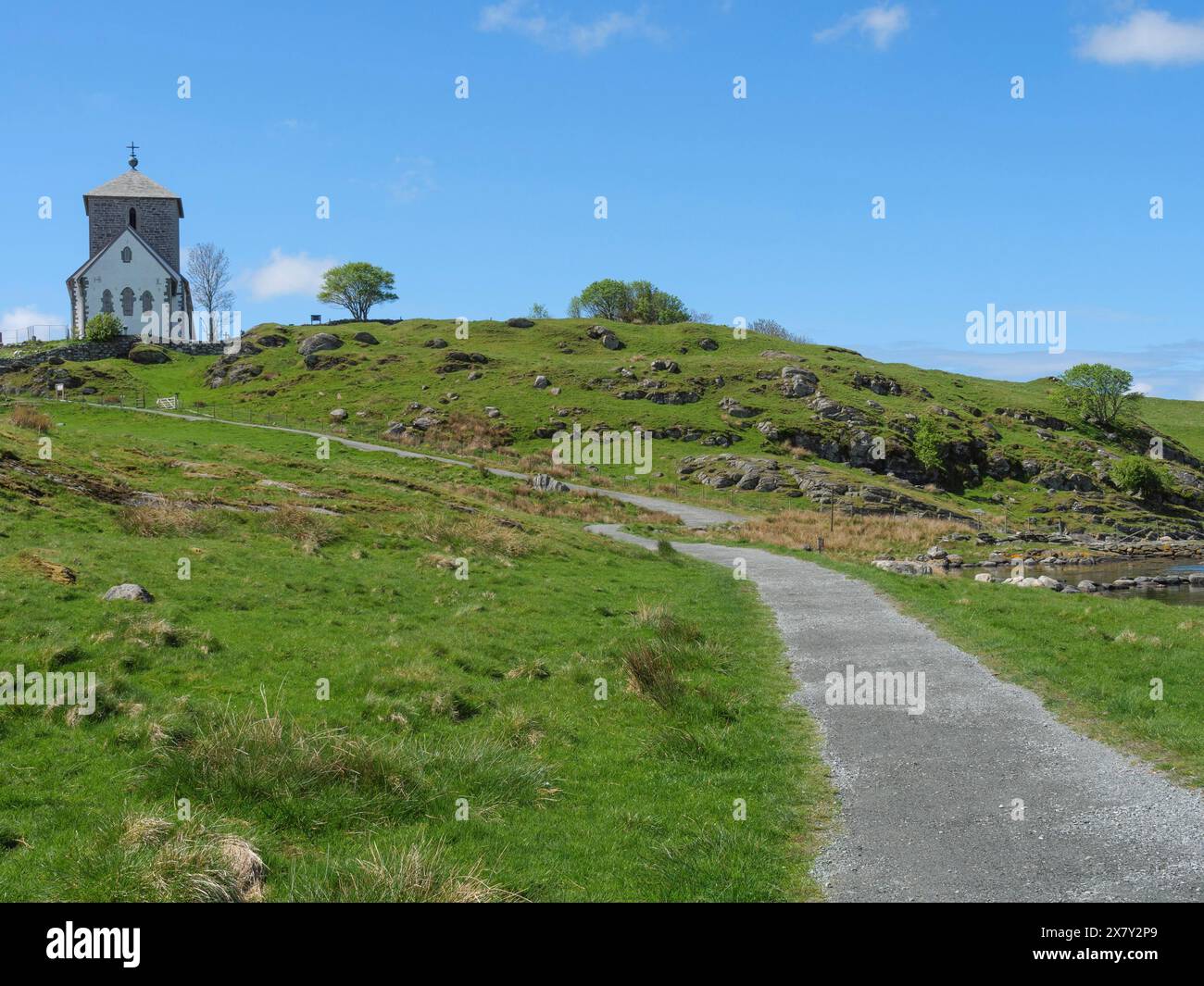 A small path leads to a church on a hill surrounded by green nature and ...