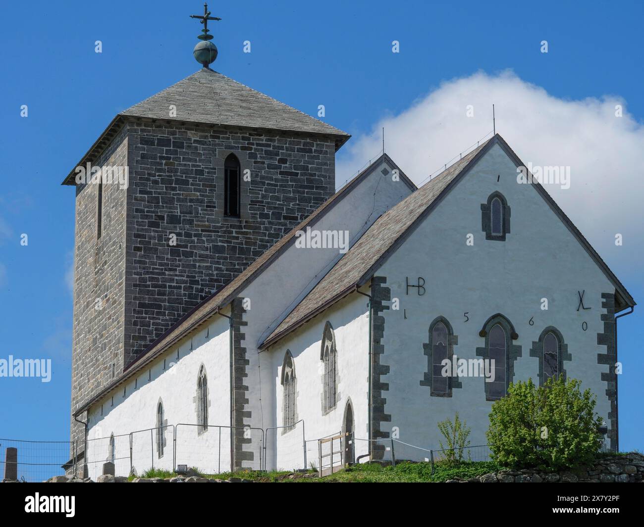 White church with stone tower in close-up, blue sky with some clouds ...