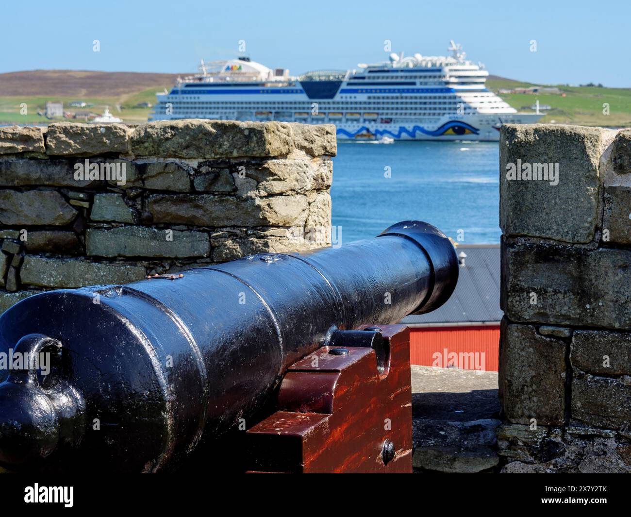 A cannon aims at a large cruise ship in the sea, old cannons on a stone ...