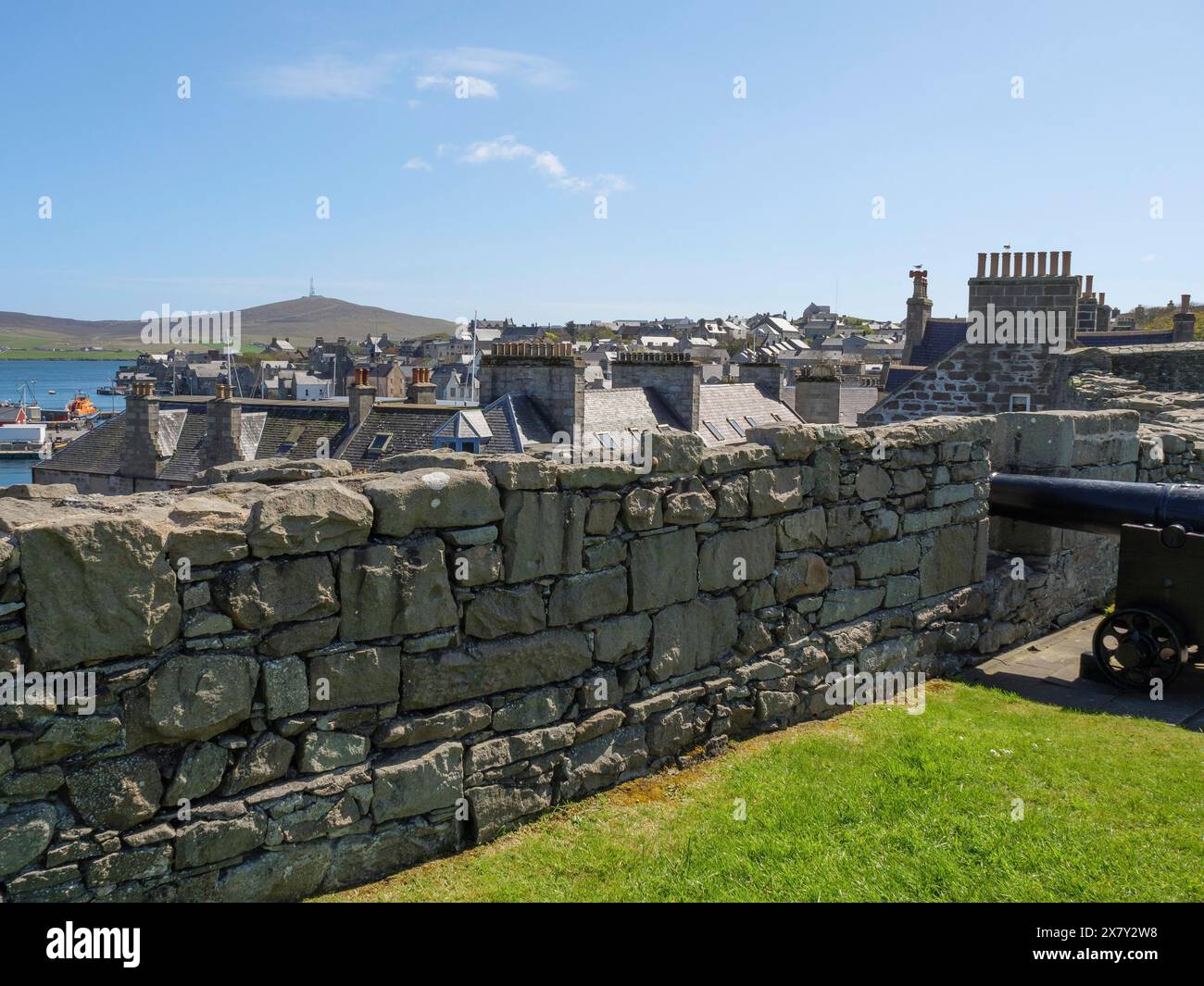 An old cannon behind a wall with a view of the town and hills, old ...