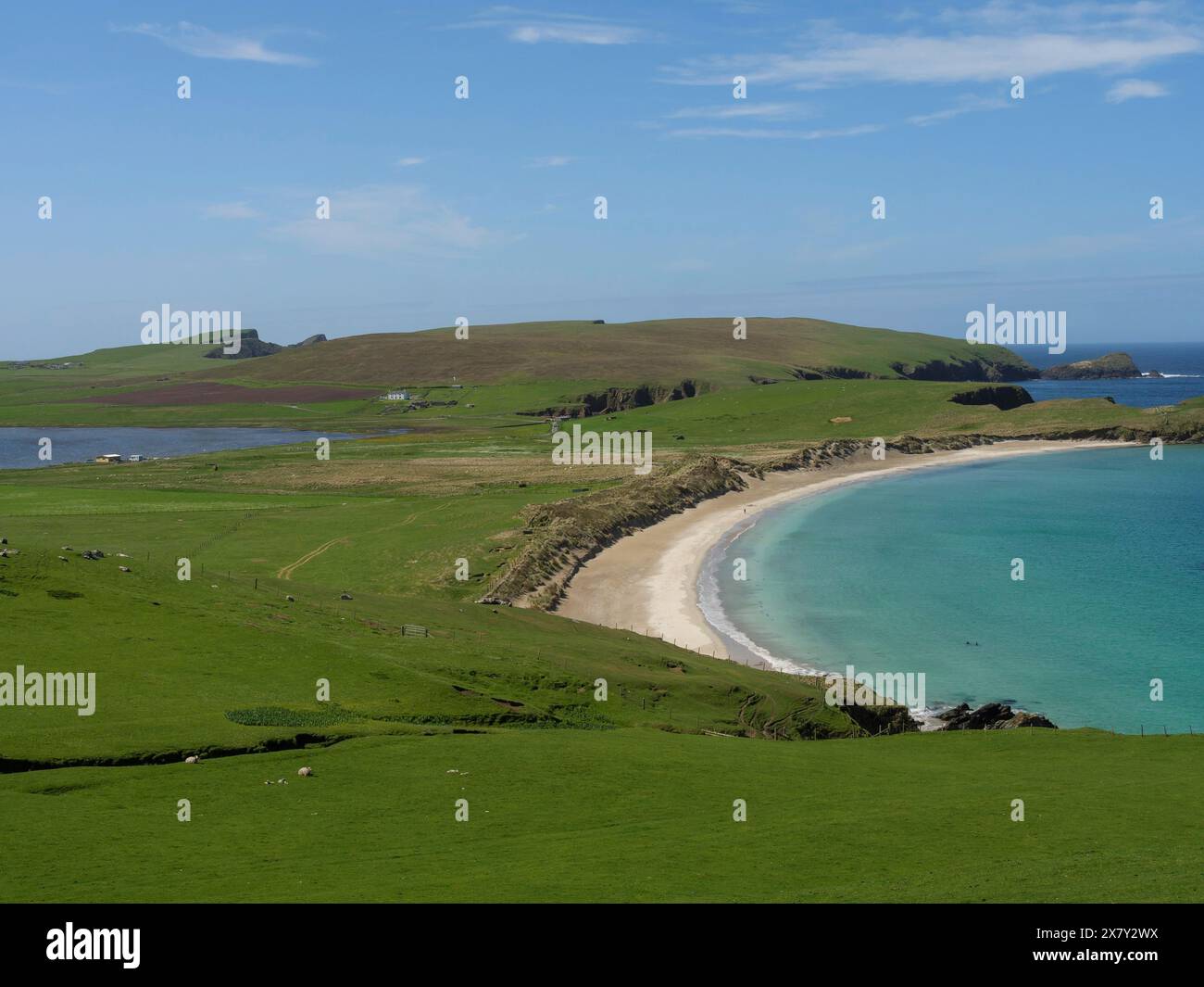 An idyllic coastal scene with rolling green hills, a long sandy beach ...