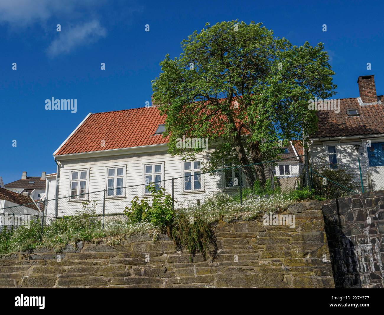 White house with red tiled roof behind a stone wall under blue sky ...