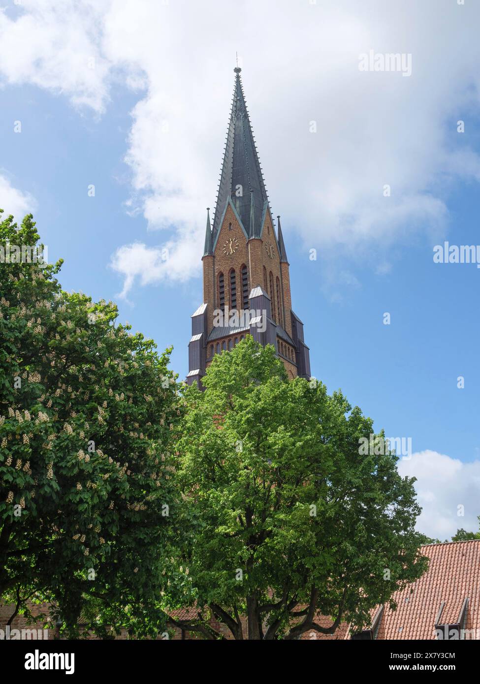 A tall church tower with a green roof rises into the overcast sky ...