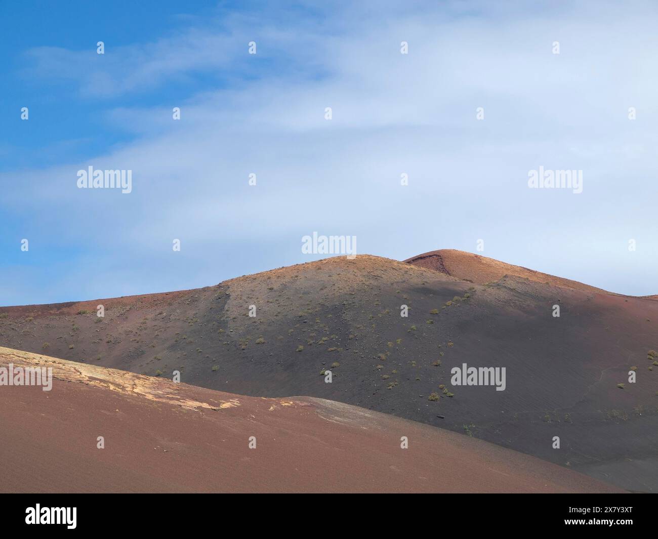 Dry, hilly desert area under a blue sky with white clouds, barren ...