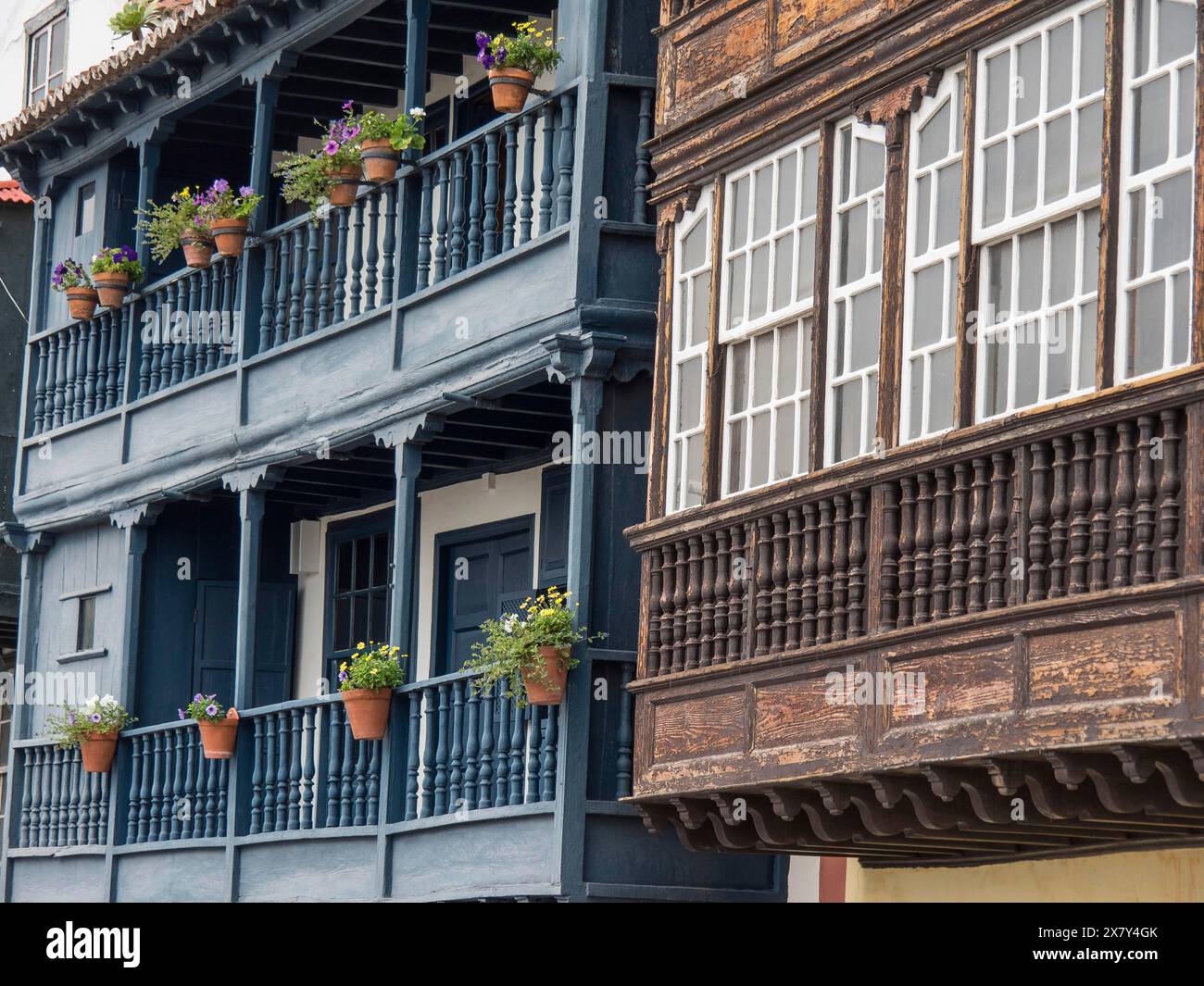 Two balconies in old architecture with numerous flower pots and wooden ...