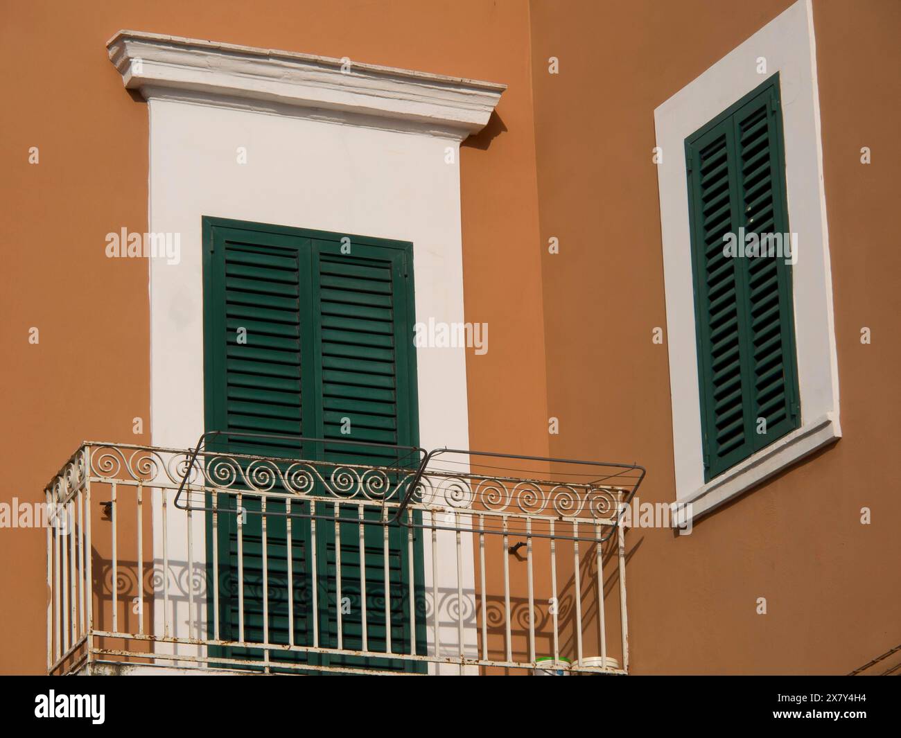 A balcony in front of an orange-coloured wall, decorated with green ...