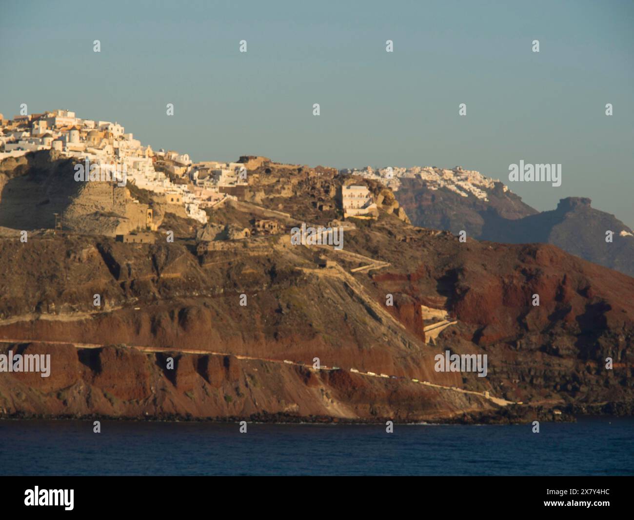 A coastline of Santorini with prominent cliffs and densely built houses ...