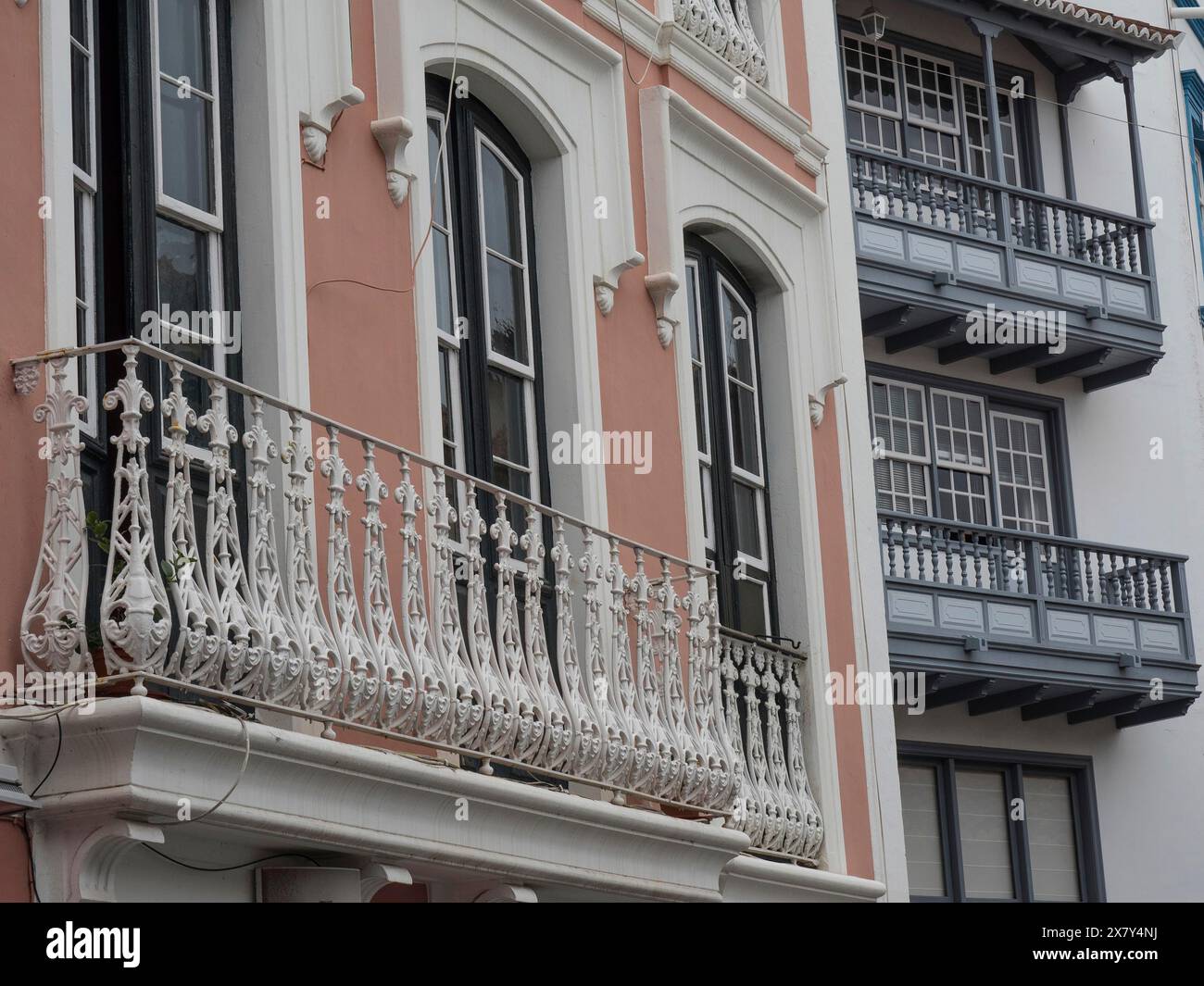 An elegant balcony with wrought iron railings and large windows ...