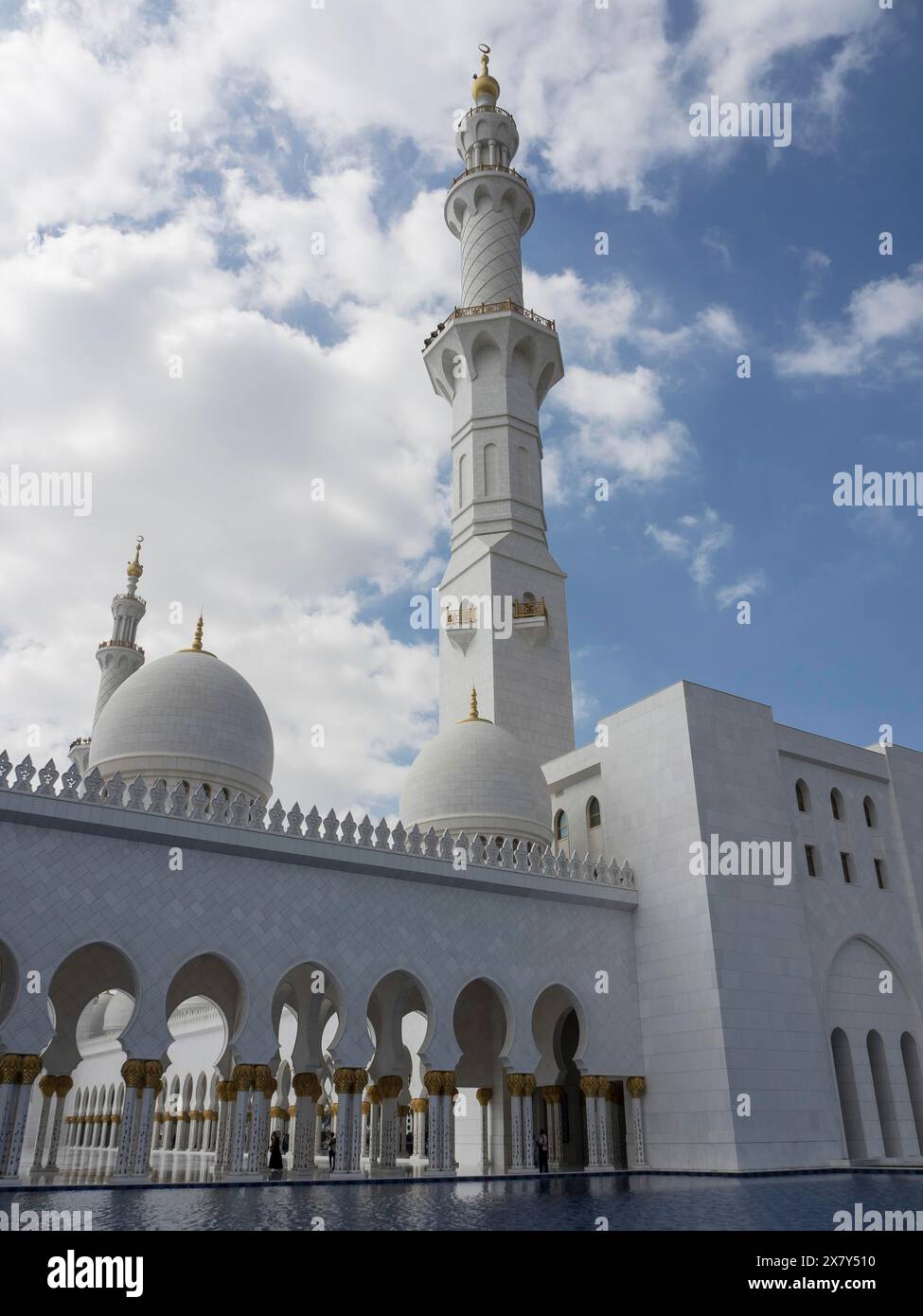 High minaret tower in front of a wide blue sky with some clouds, white ...
