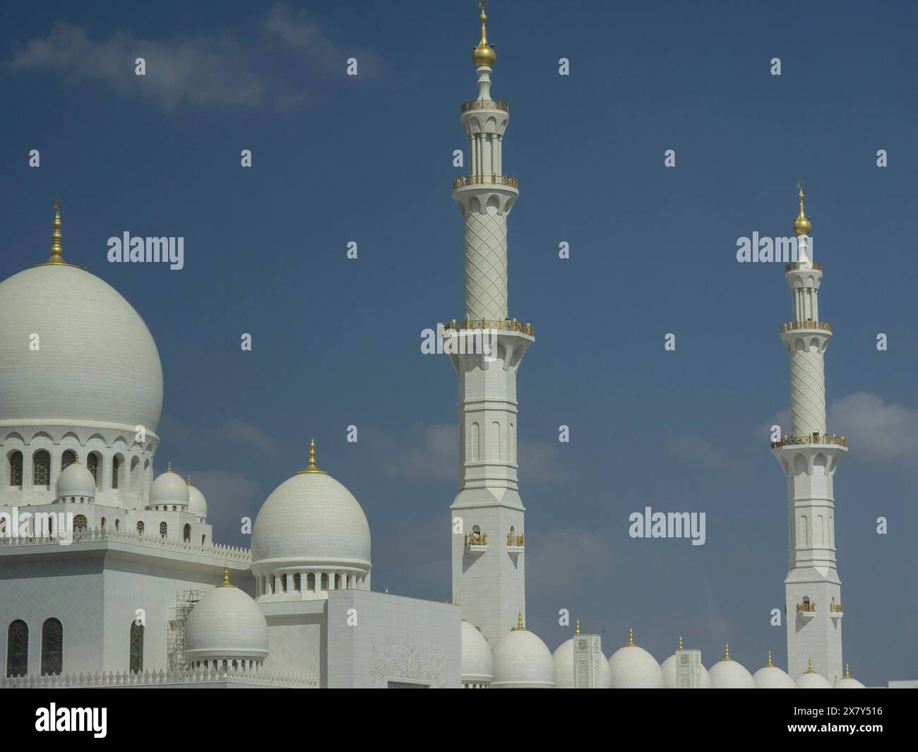Large white mosque with magnificent domes and slender minarets against a blue sky, large mosque ...